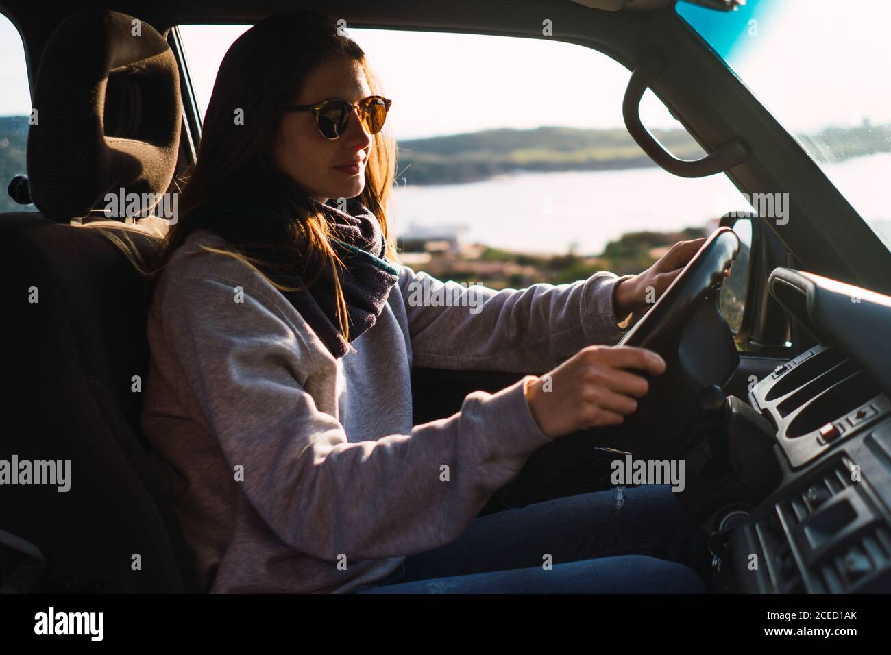 Side view of young Woman sitting and driving a car in the nature Stock ...