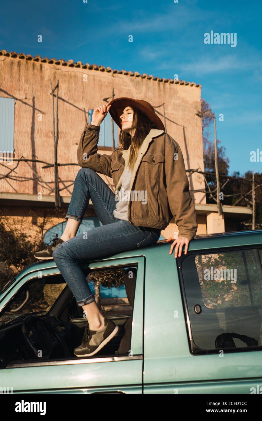 Woman sitting on car roof Stock Photo - Alamy