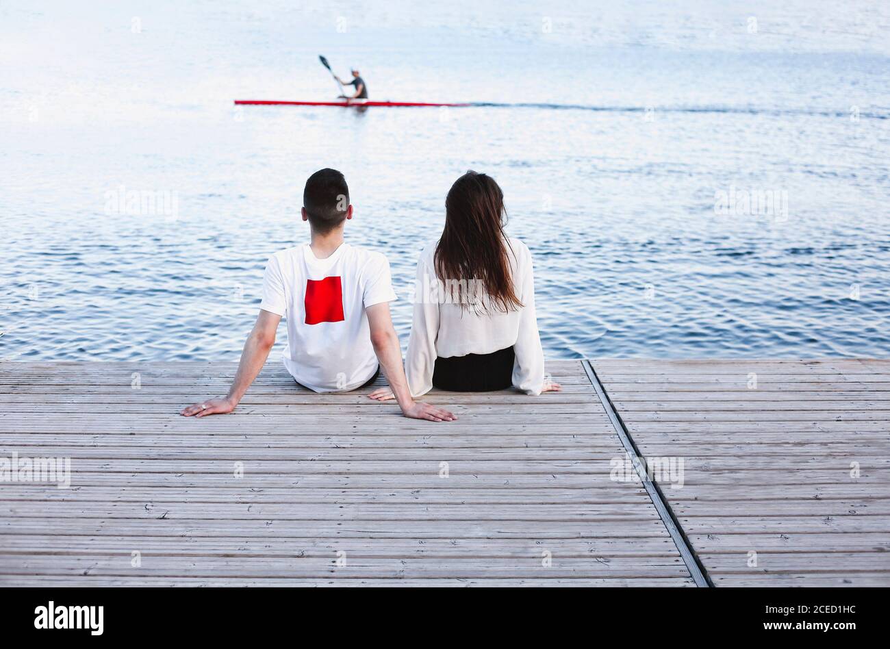 Back view of young happy girlfriend and boyfriend sitting on wooden ...