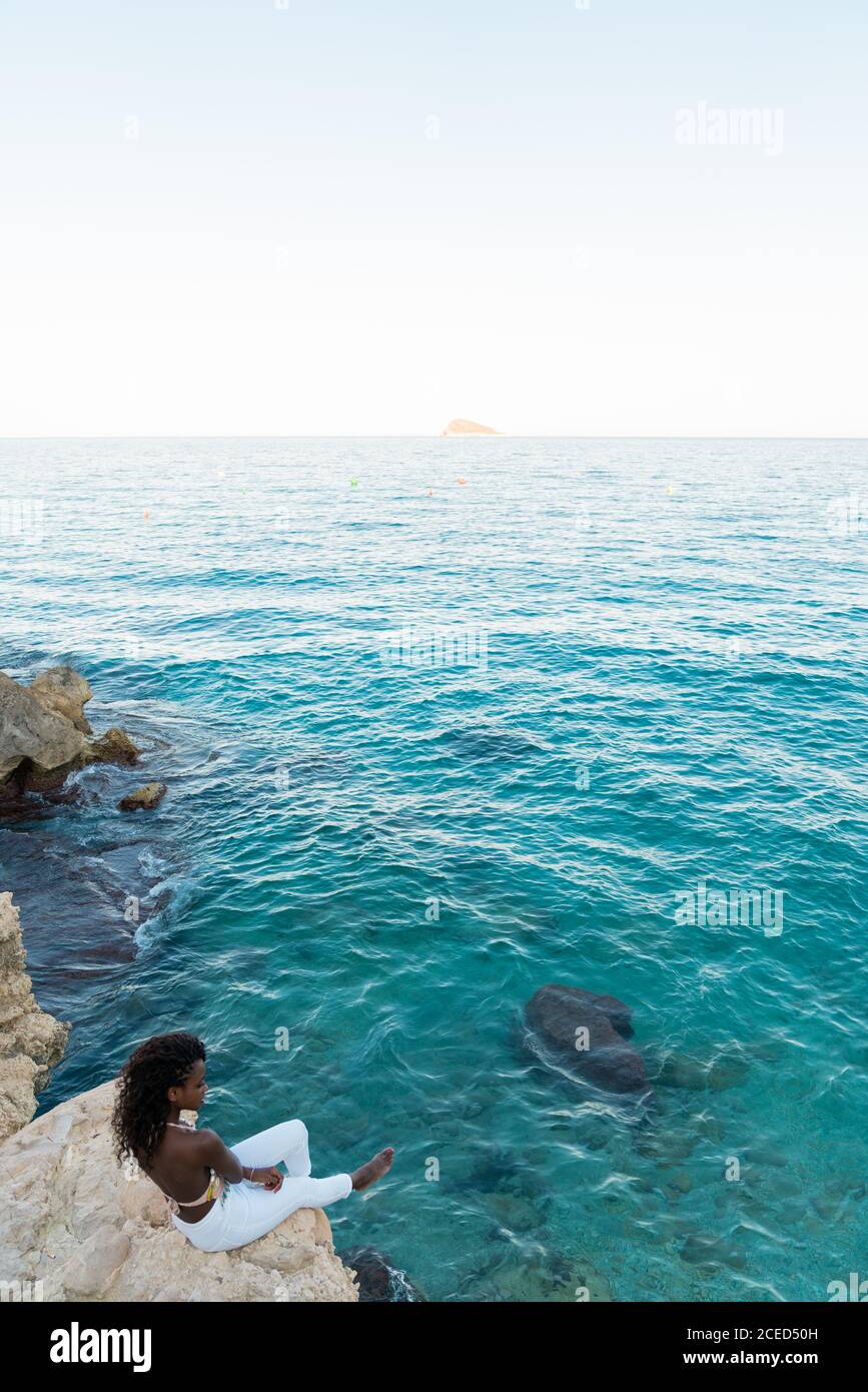 Woman sitting on cliff above water Stock Photo - Alamy