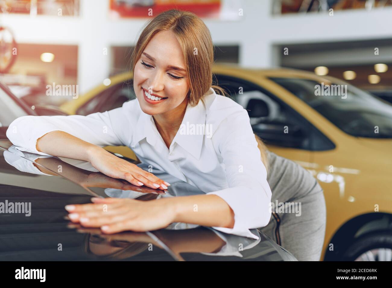 Beautiful young woman touching her new car with pleasure Stock Photo ...