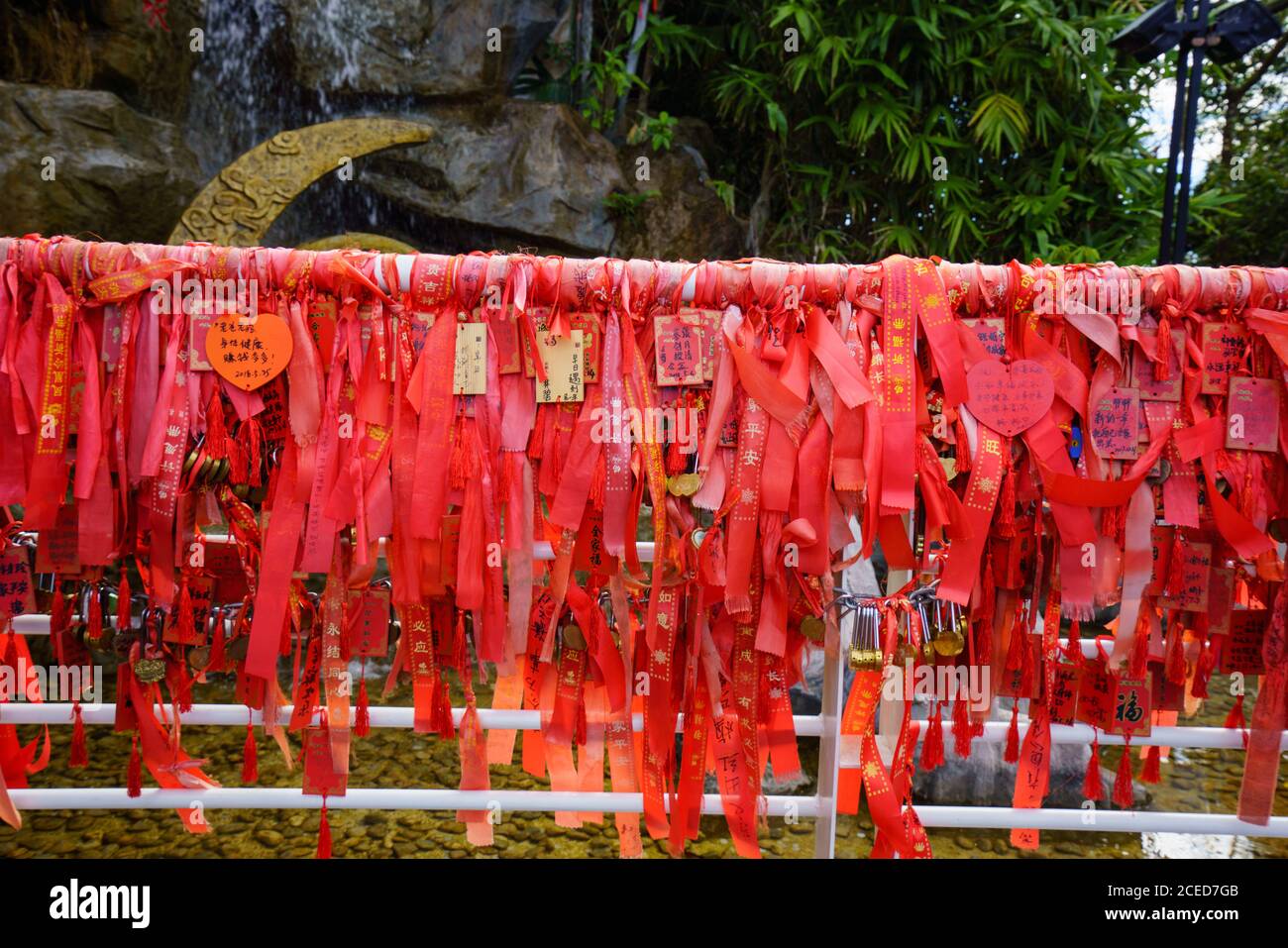 White fence with plenty of hanging bright red wish ribbons in on green ...