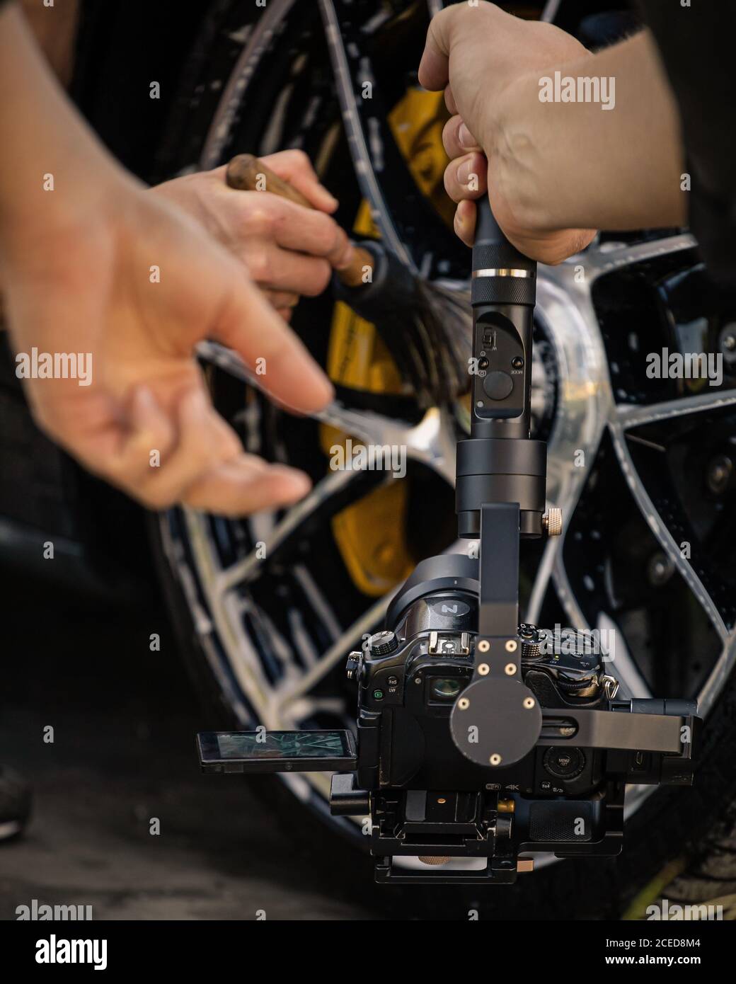 Vertical shot of workers fixing the wheel of a car Stock Photo - Alamy