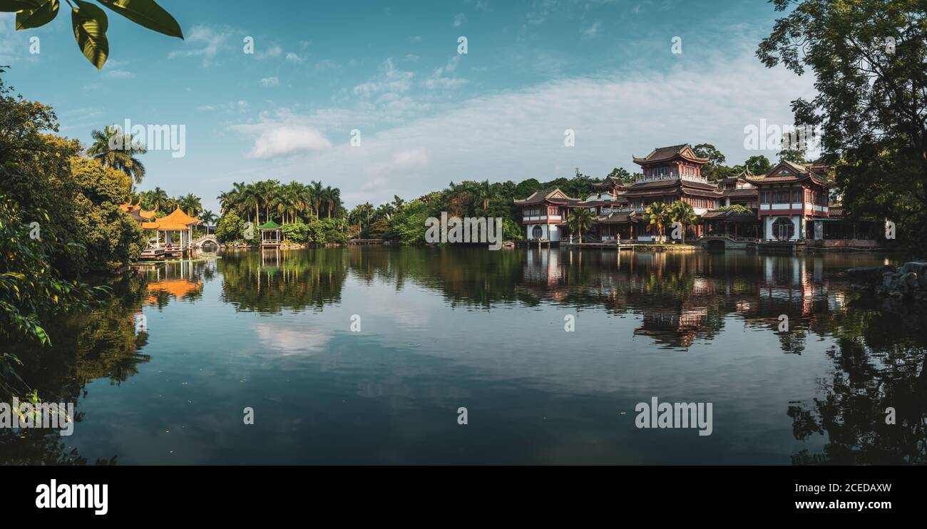 View of calm lake water reflecting sky and oriental buildings on shore ...