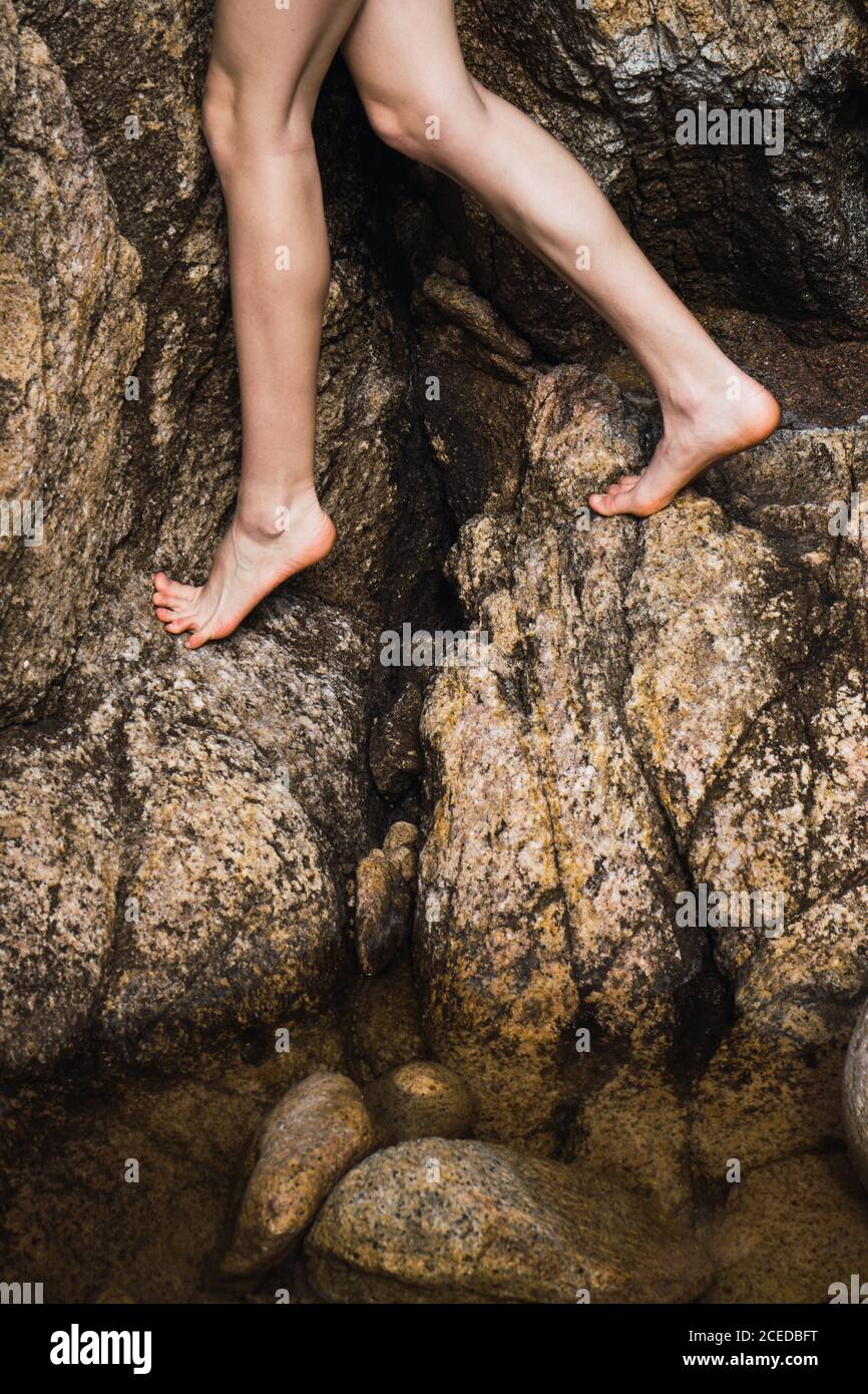 Crop unrecognizable barefoot Woman stepping on rough rocks Stock Photo ...