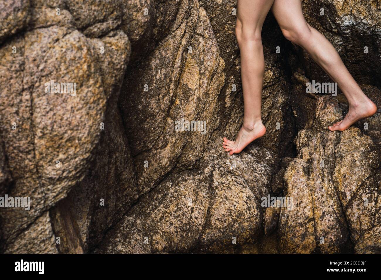 Crop unrecognizable barefoot Woman stepping on rough rocks Stock Photo ...