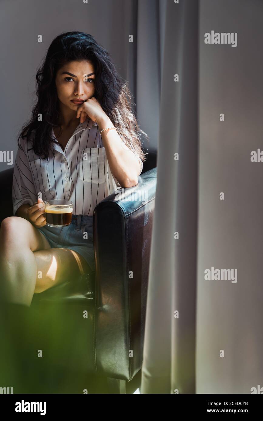 Woman sitting with coffee near window Stock Photo - Alamy