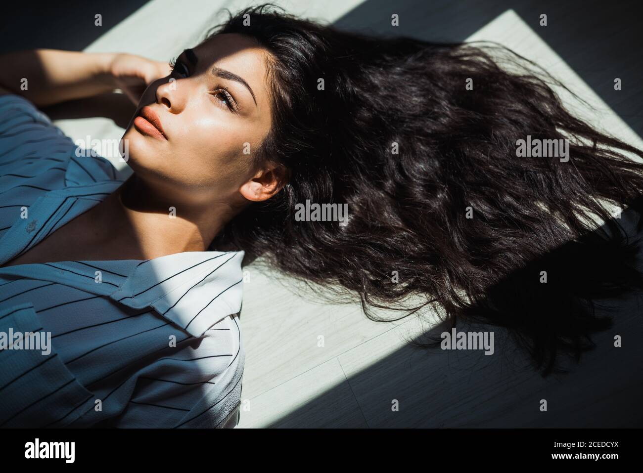 From above of young provocative Woman with long black hair lying spread ...