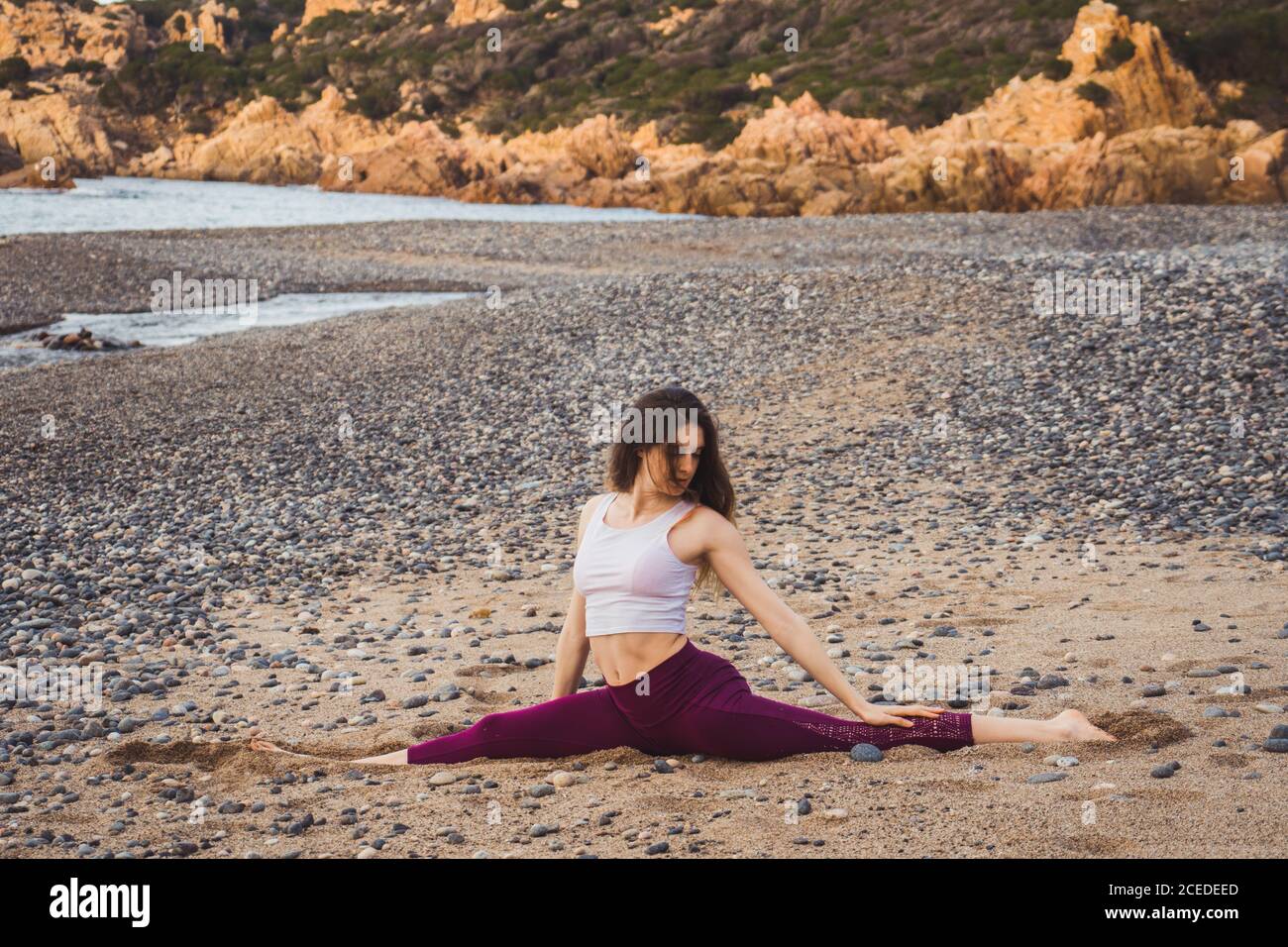Pretty fit Woman sitting and stretching in string pose on shore at the ...