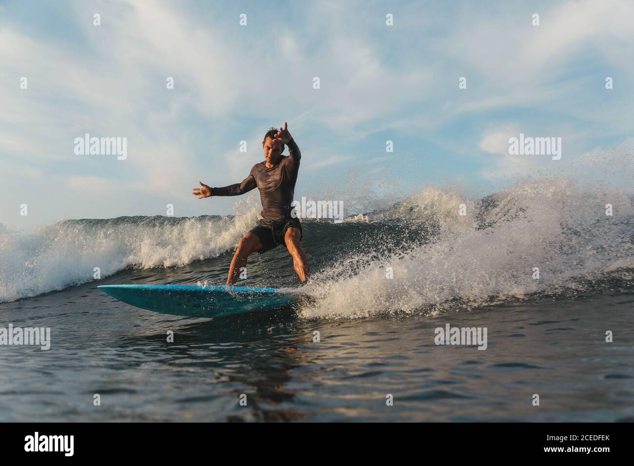 Male surfing between waving water of sea with splashes in Bali ...