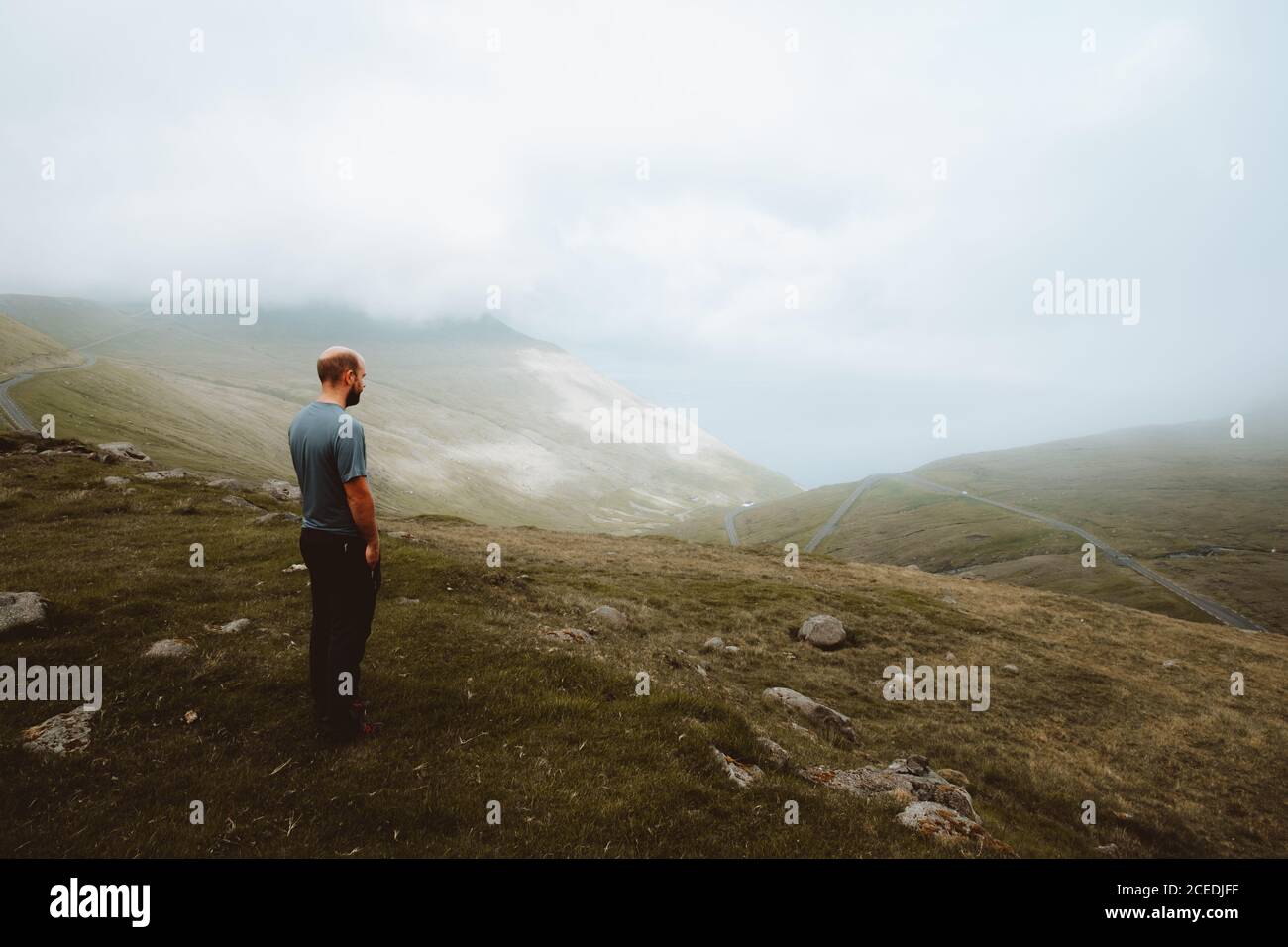 Back view of unrecognizable hiker man standing on coast with stick and ...