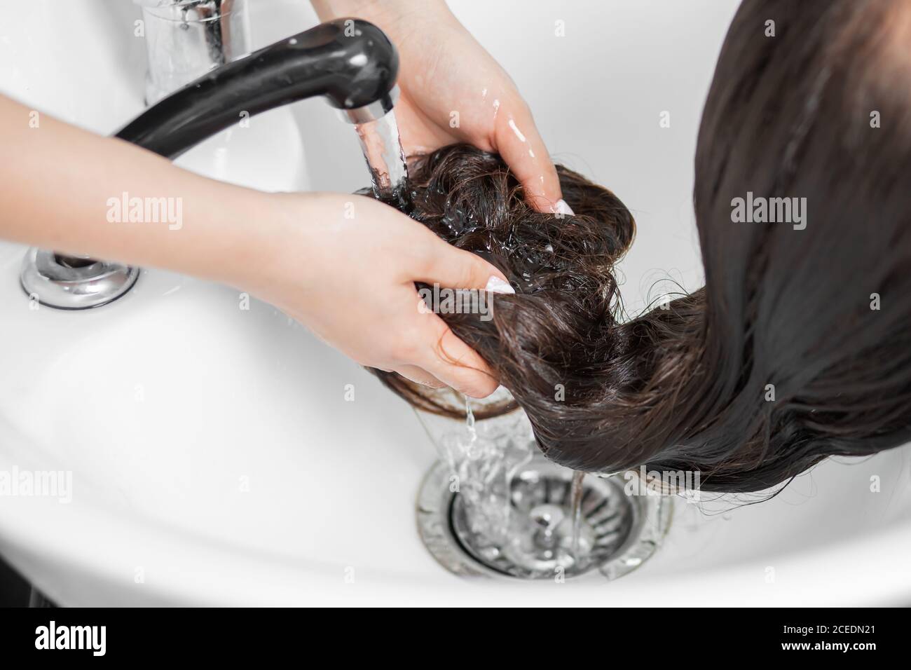 Shampooing hair in spa beauty salon, hairdresser washes foam from head ...