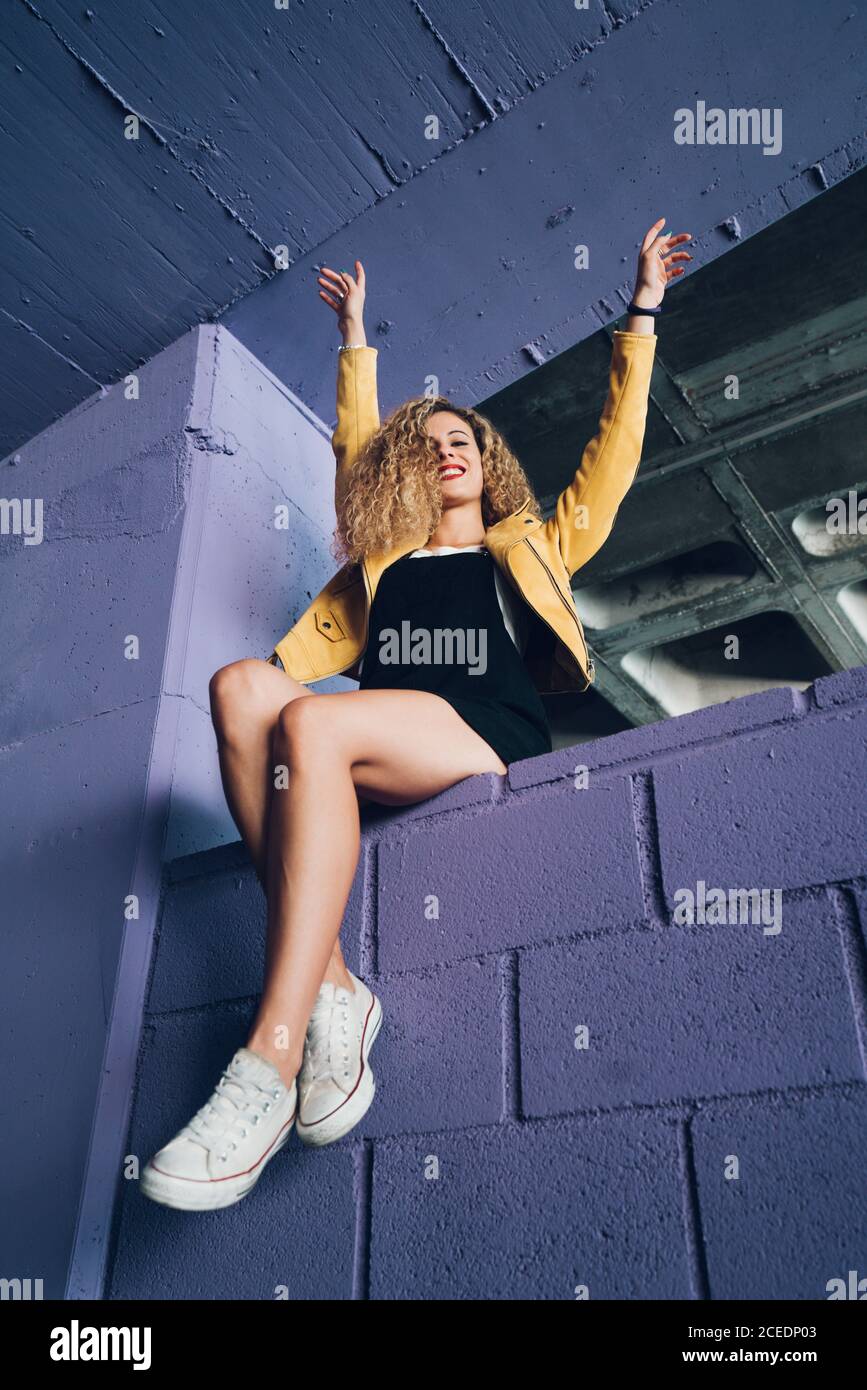 From below side view of stylish curly blonde in sneakers and yellow ...