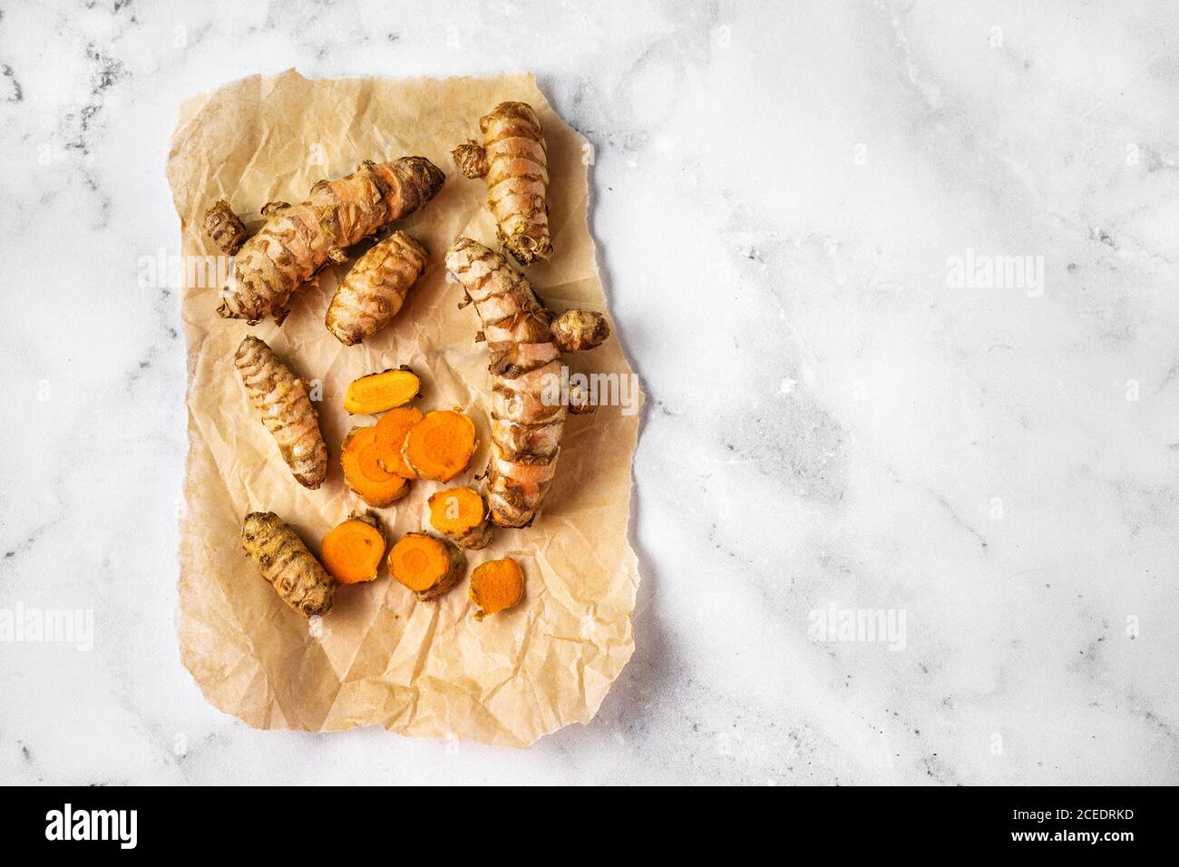 Top view of turmeric curcuma roots on crumpled paper and white surface ...