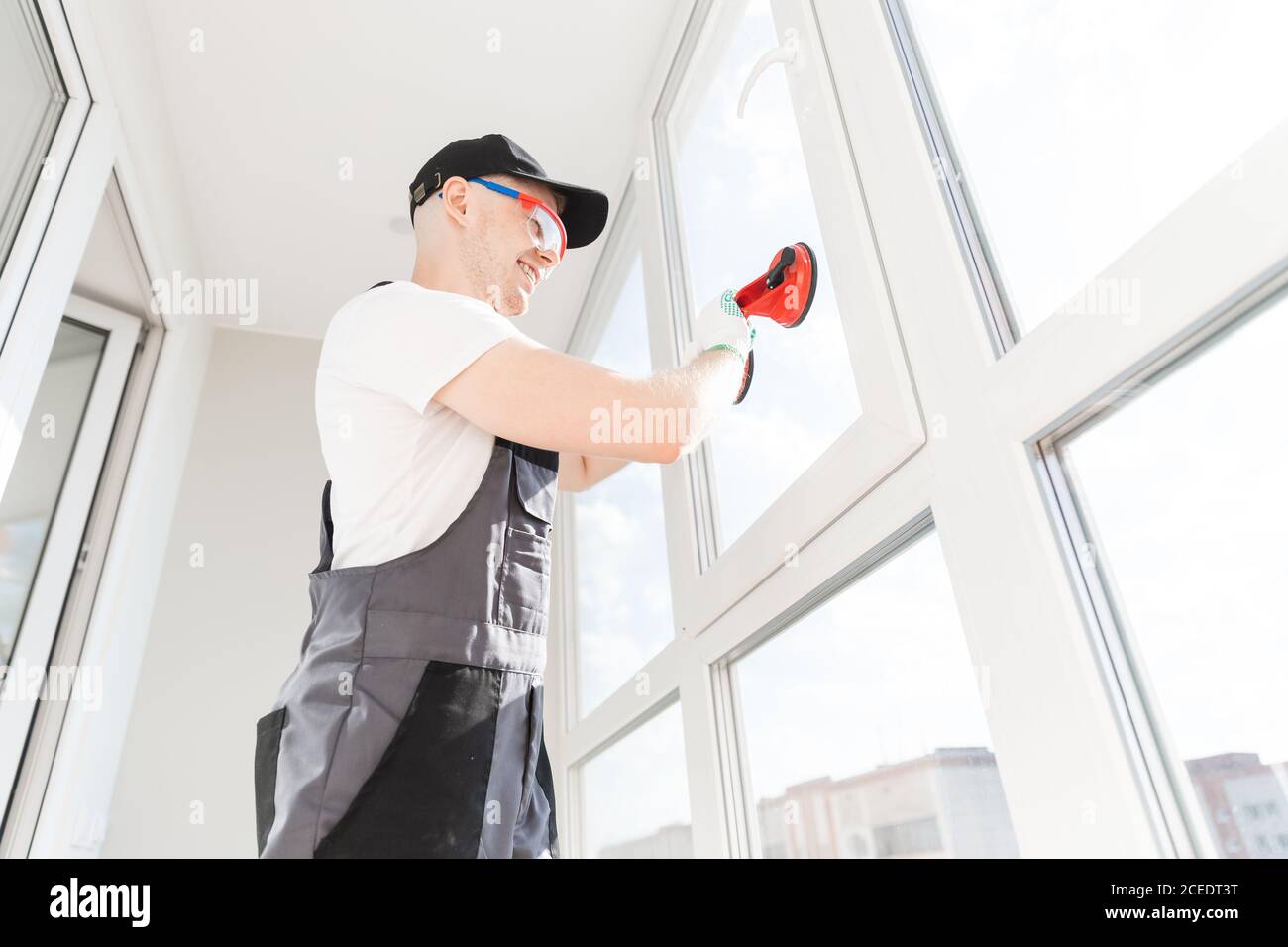 Worker man installs plastic windows and doors with double-glazed white ...