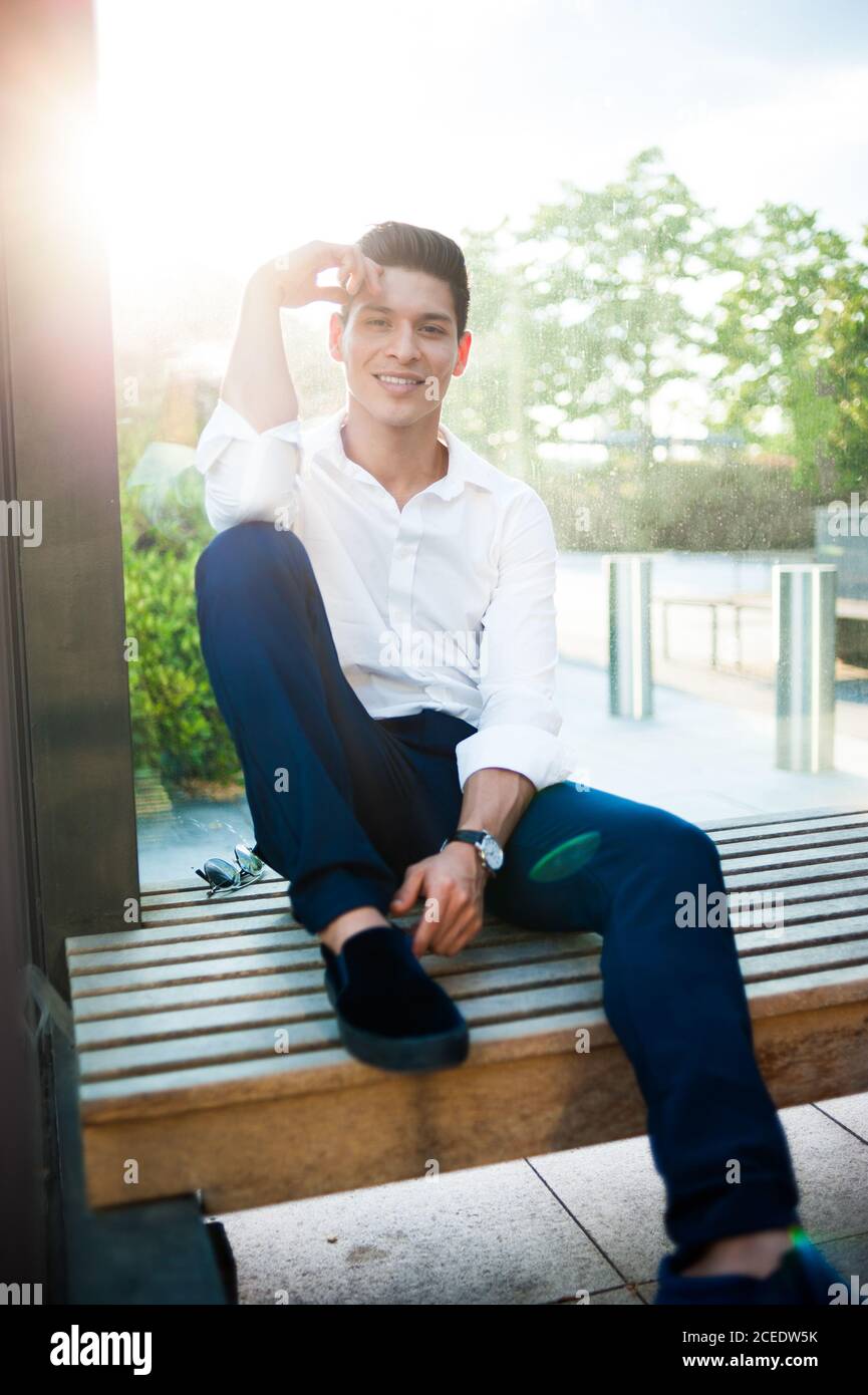 Smiling modern man on bench Stock Photo - Alamy