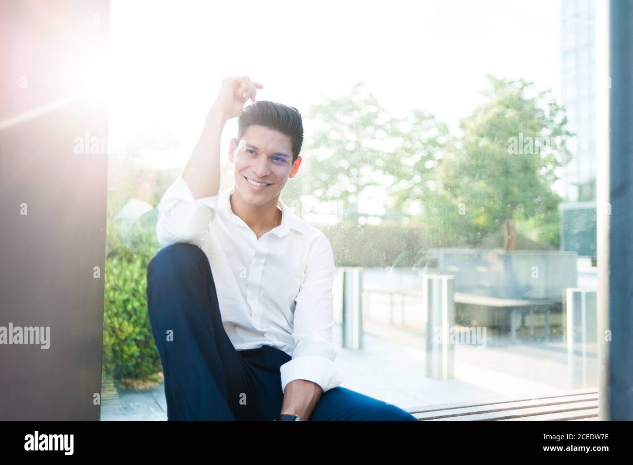 Smiling modern man on bench Stock Photo - Alamy