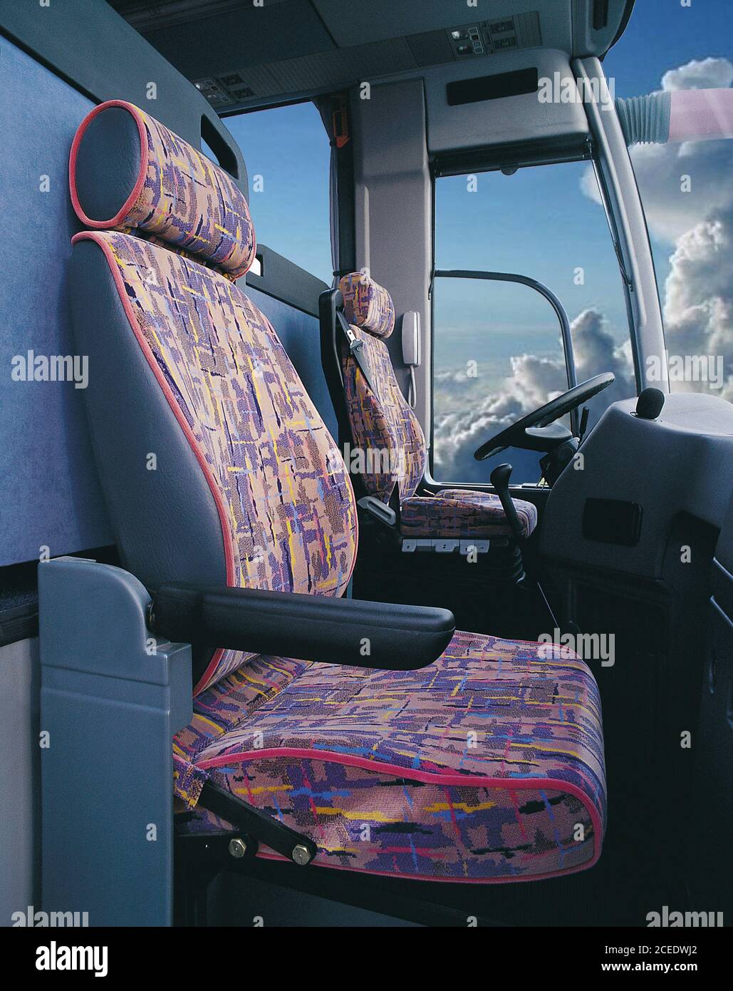 Driver's compartment of an old bus, seat, steering wheel and blue sky ...