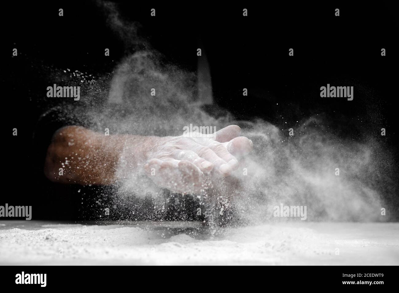 White powdery flour spraying into air while man hand baker cook on ...