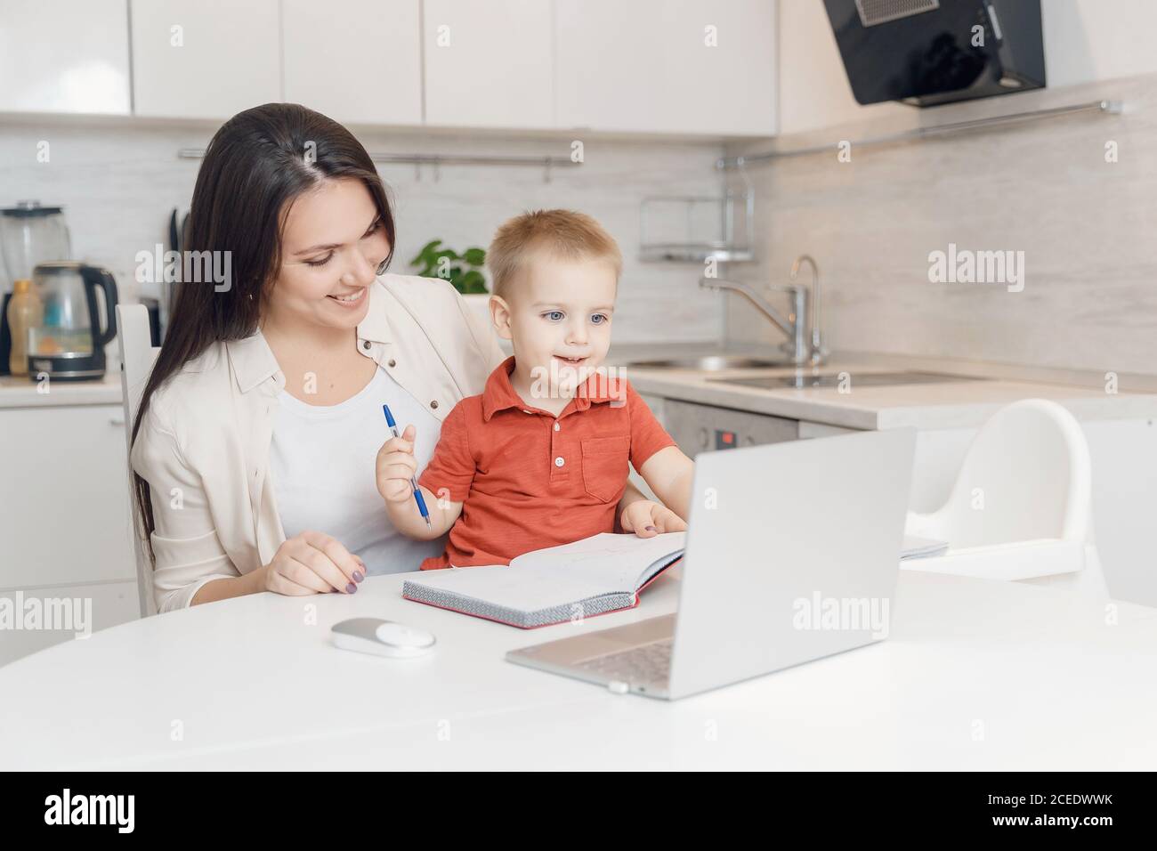 Mother and son are learning to write. Woman teaches kid alphabet Online ...