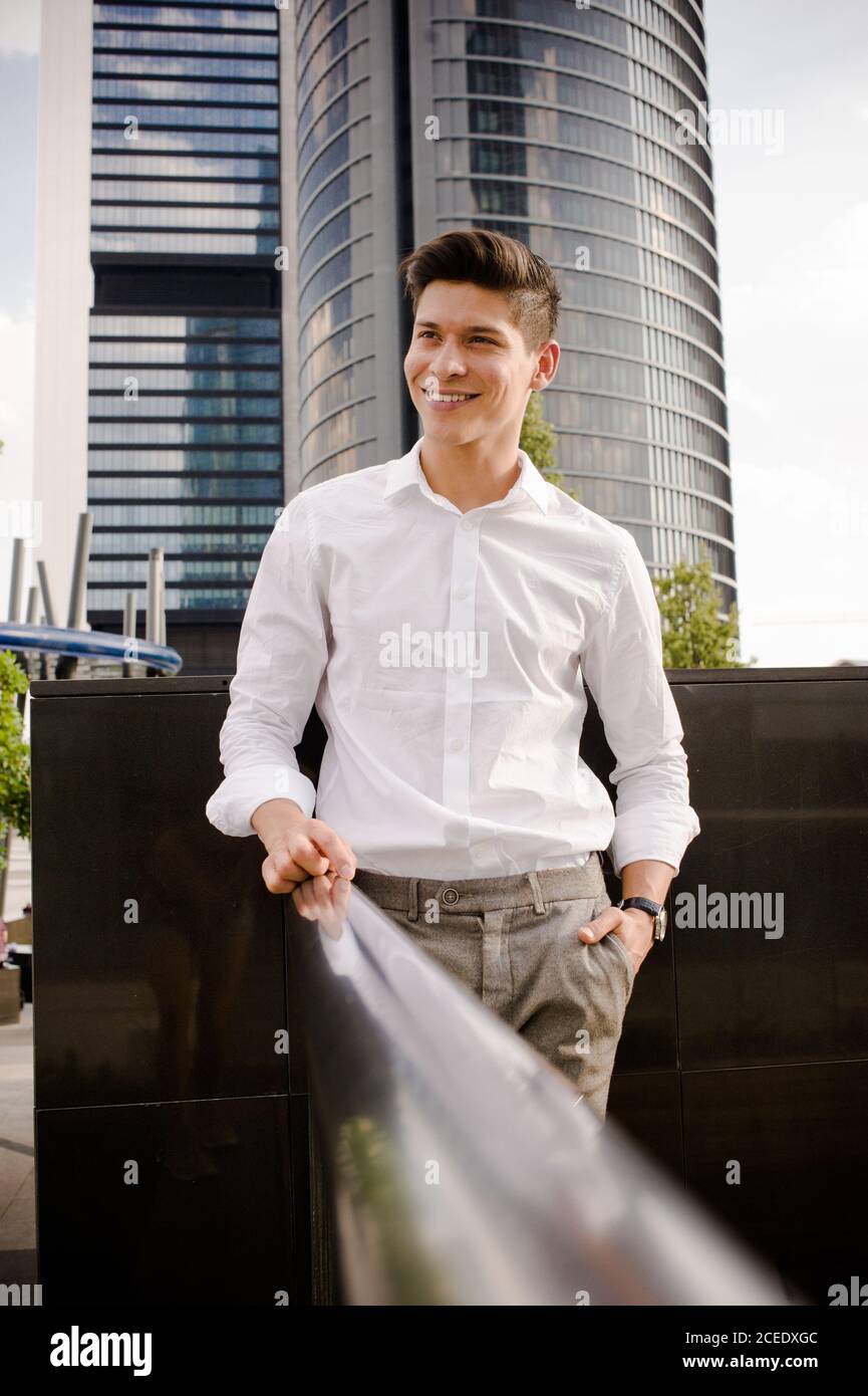 Handsome young man in elegant outfit smiling and looking away while ...