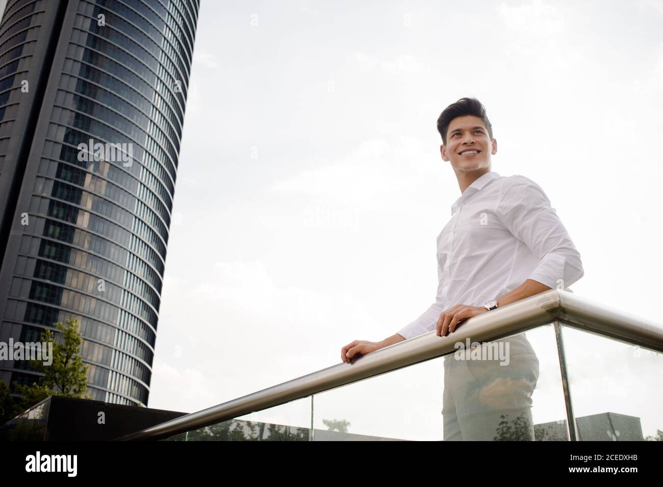 Young man leaning on railing Stock Photo - Alamy