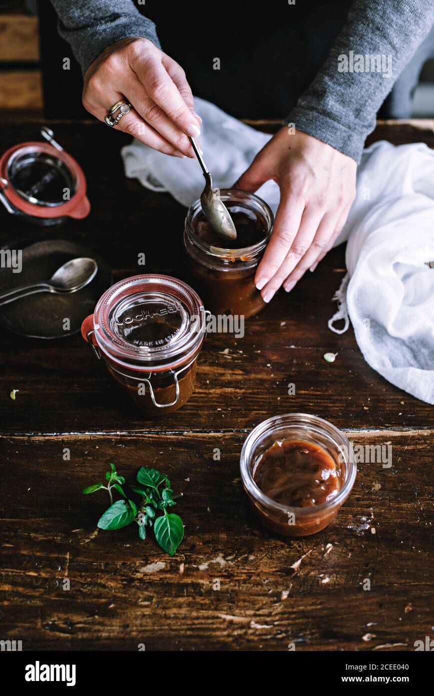 From above shot of hands of anonymous Woman using spoon to take thick ...