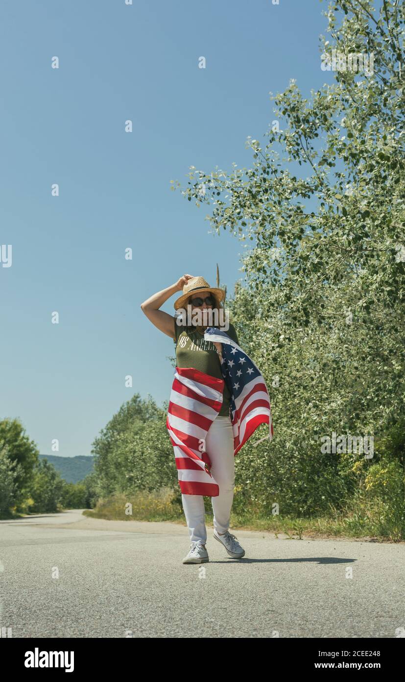 happy Woman walking with an american flag and celebrating on a lonely ...