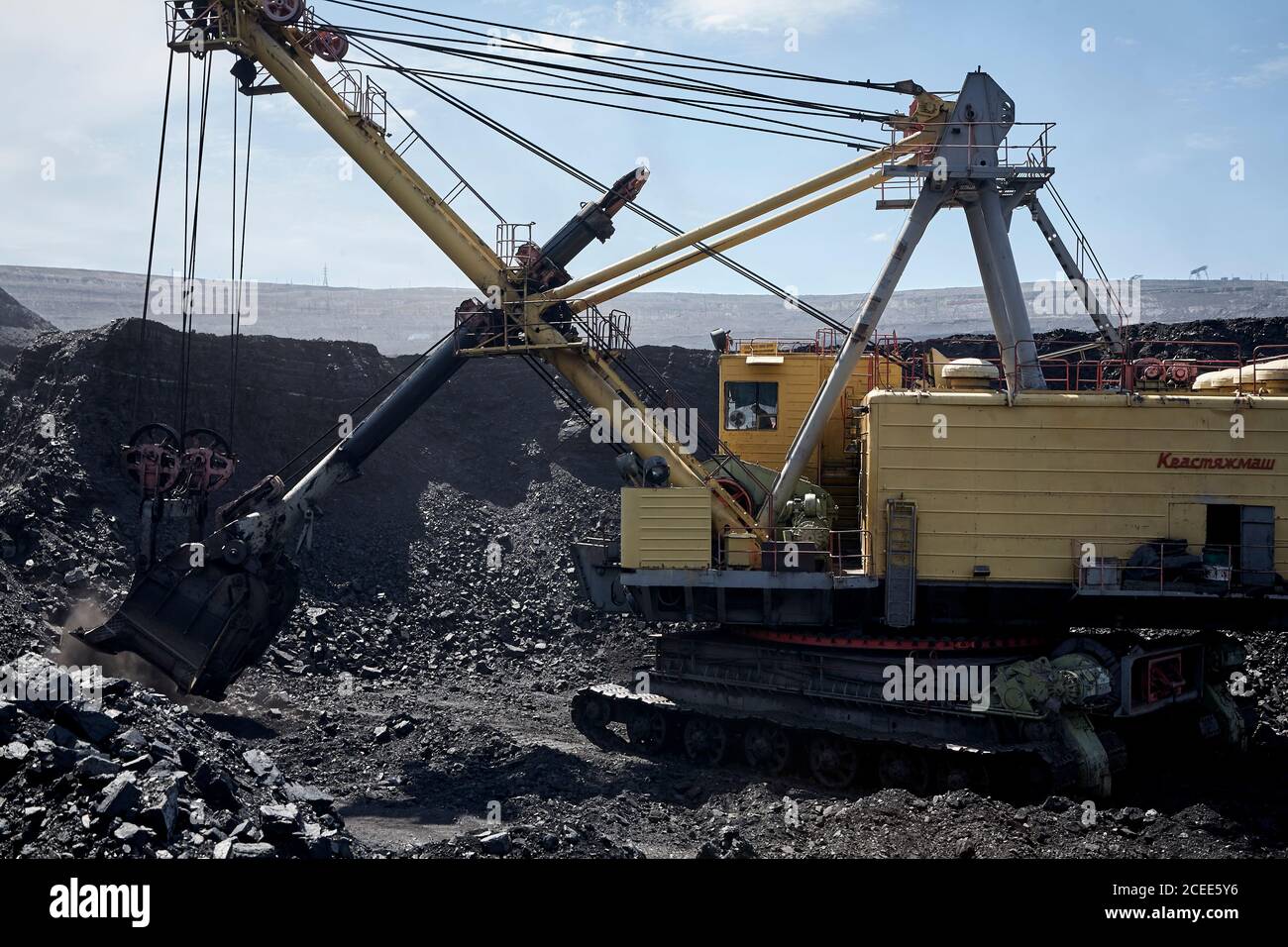 A coal mine in Kazakstan. Black coal and a big yellow machine digging ...