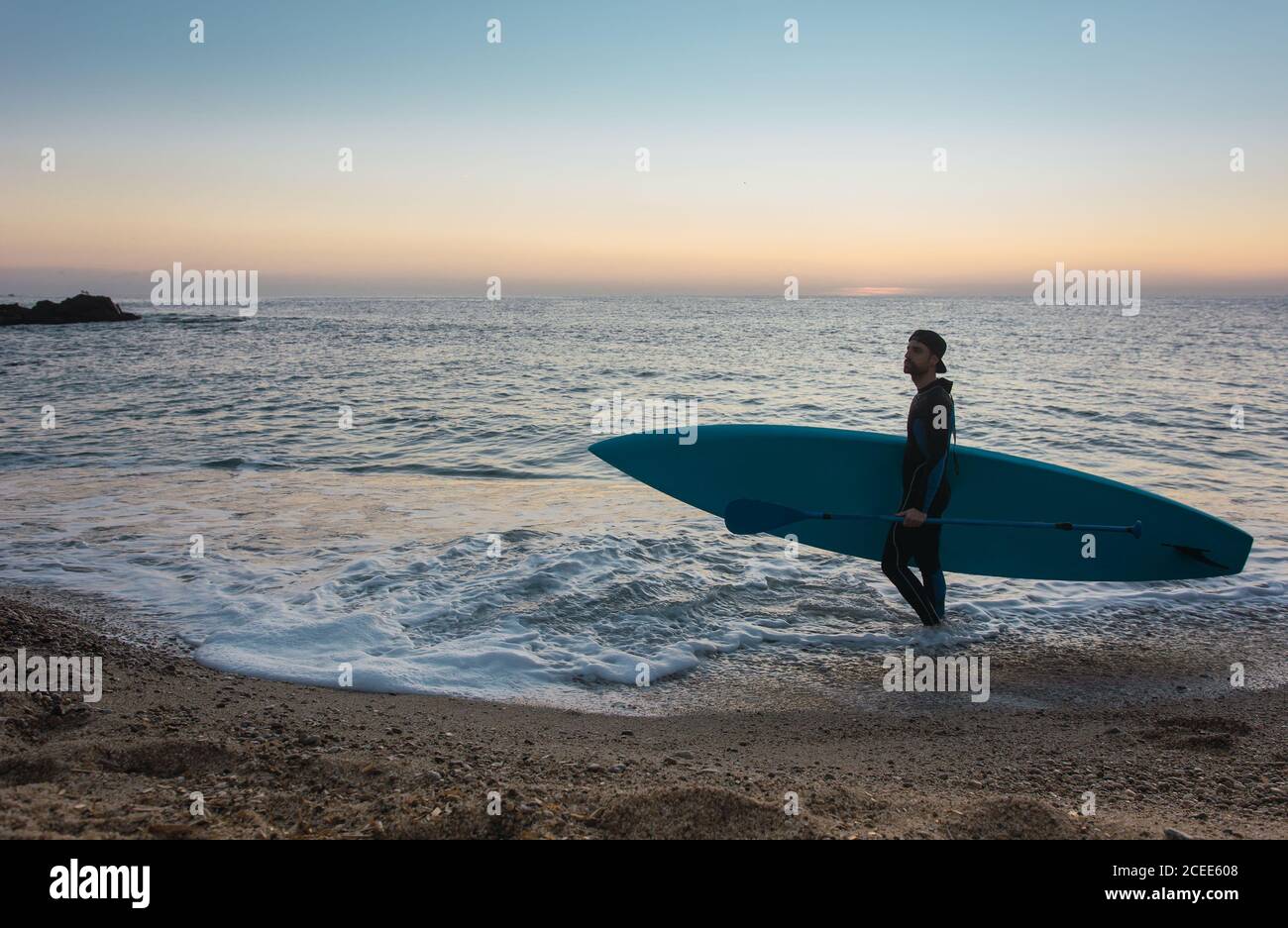 man practicing paddle surfing with neoprene in a sunrise on a ...