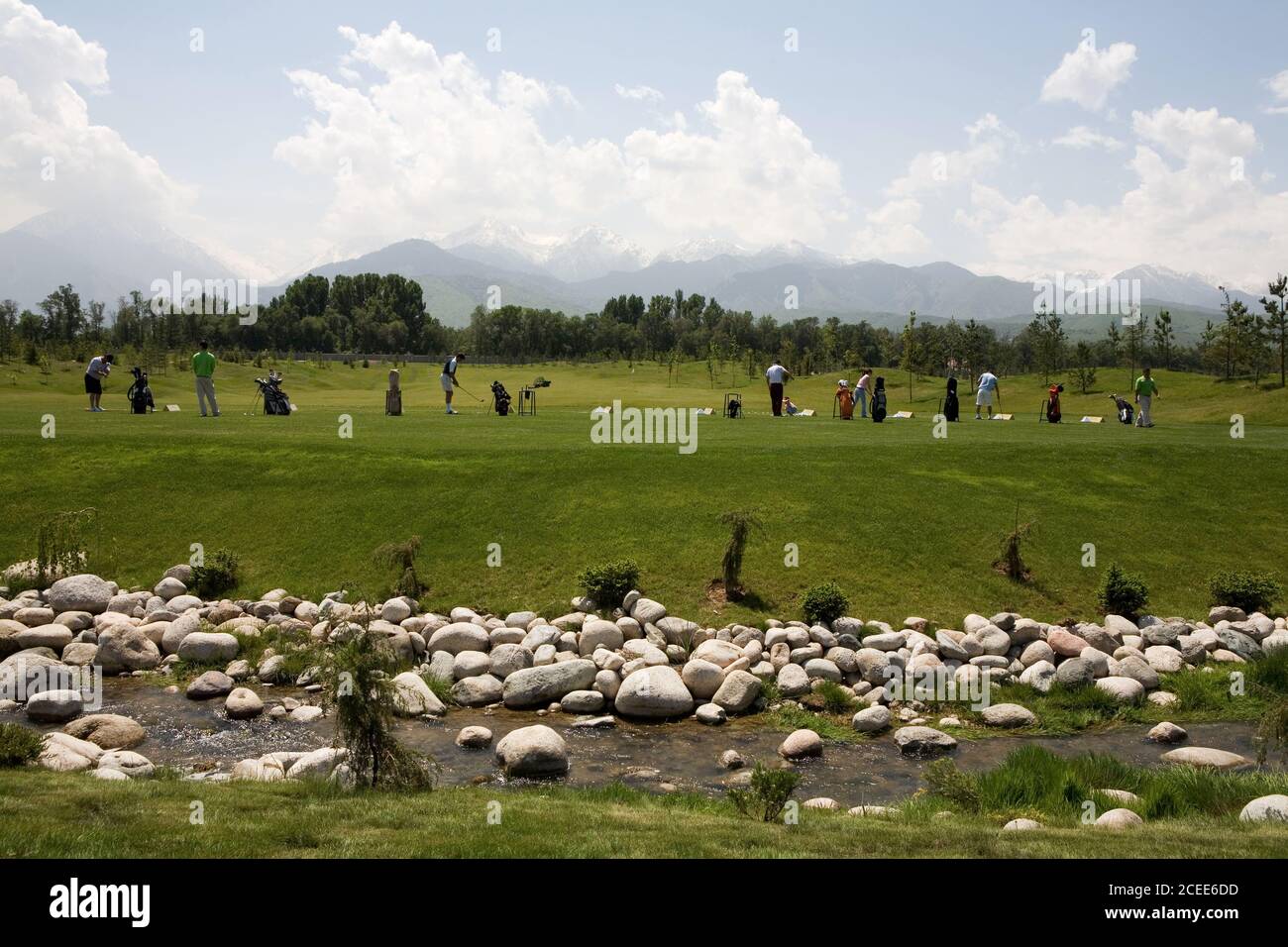Golf players on big, green driving range in Scotland. Stones in front ...