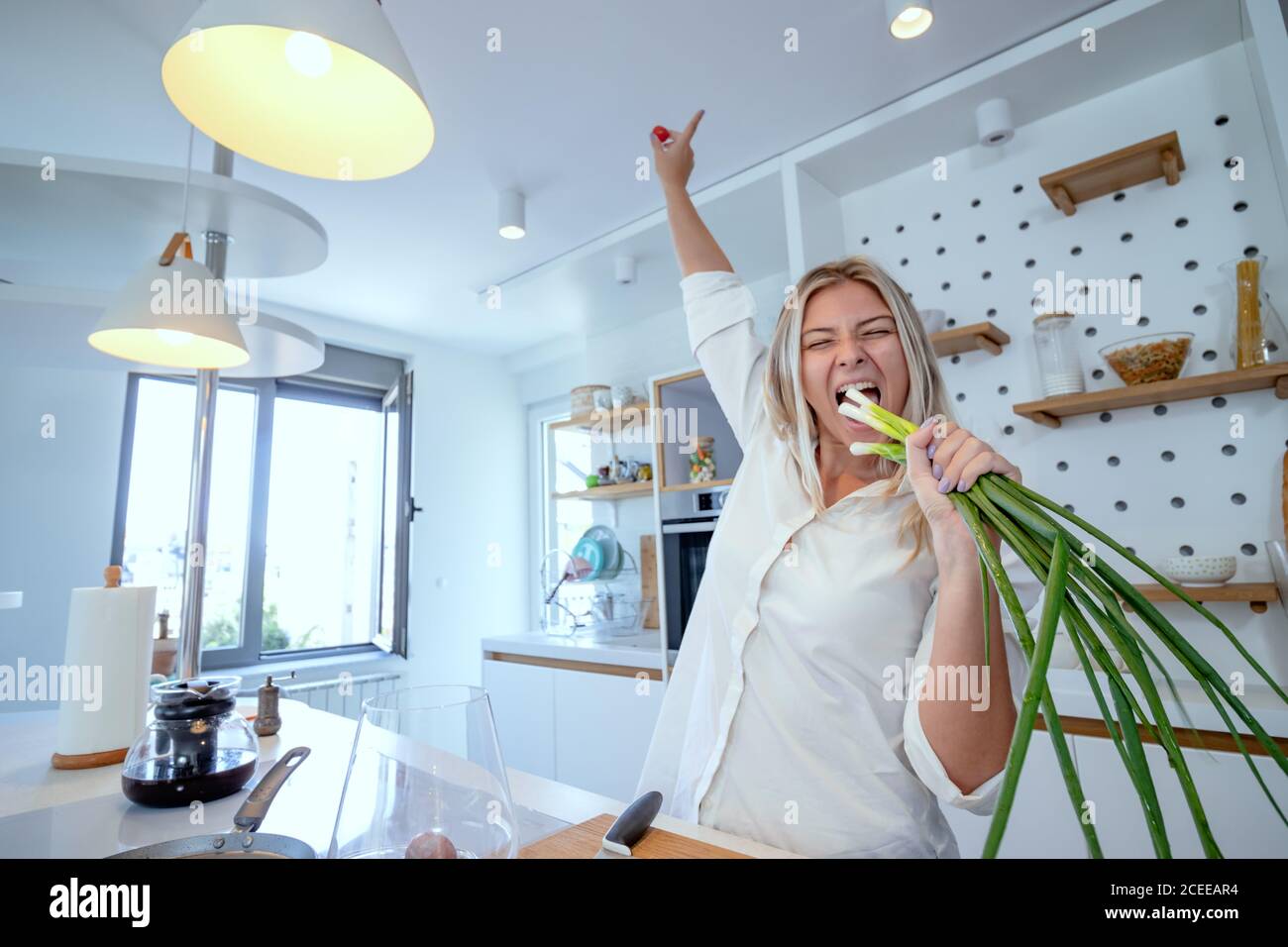 Beautiful young woman cooking in a modern kitchen. Taking a little ...