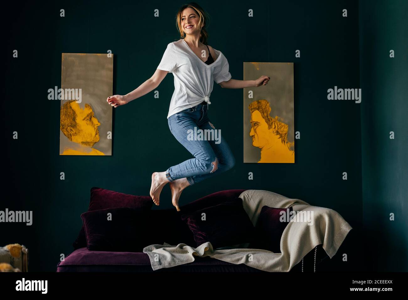 Young woman jumping on sofa hi-res stock photography and images - Alamy