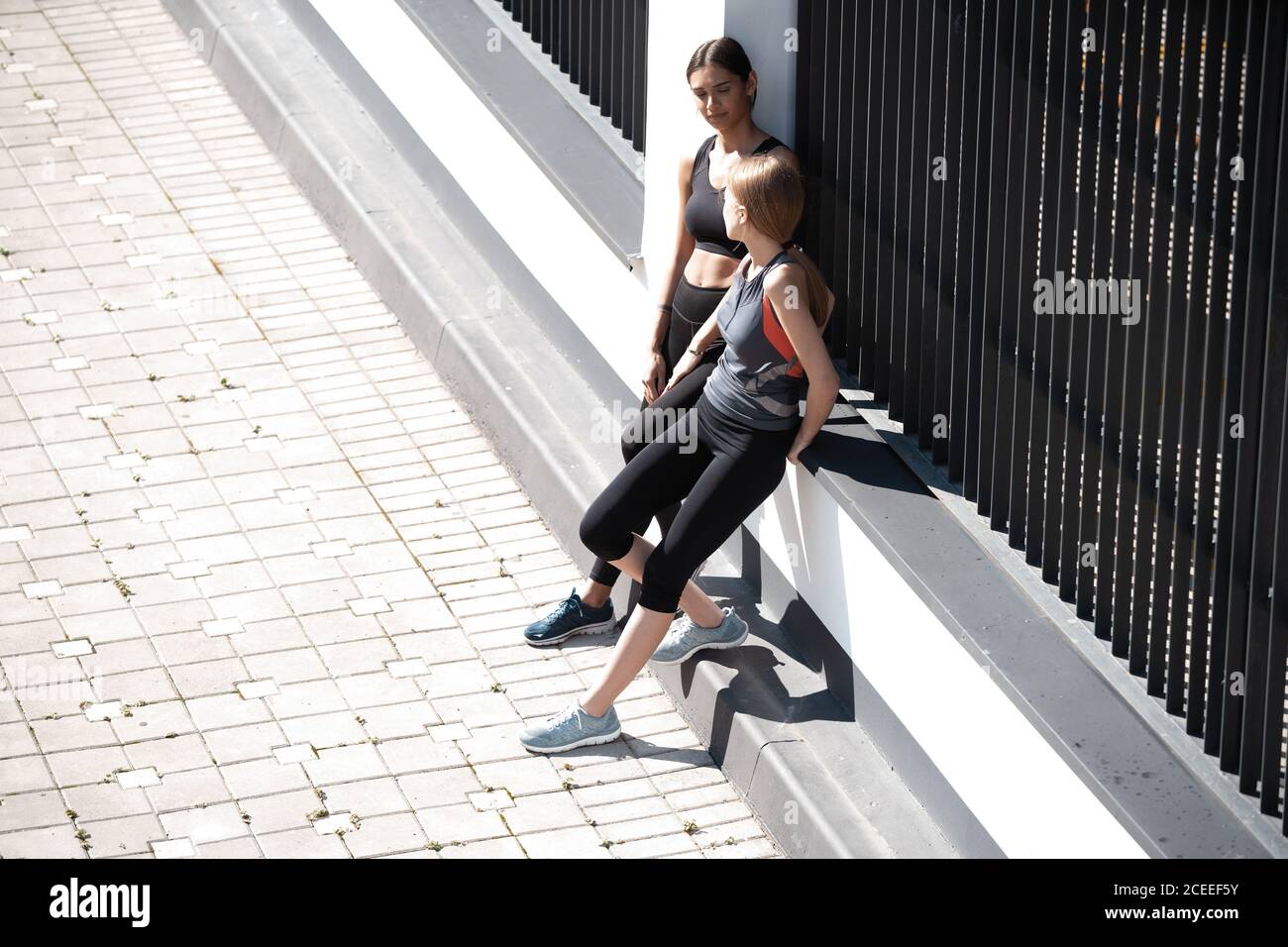 Two female friends relax after running in city Stock Photo - Alamy