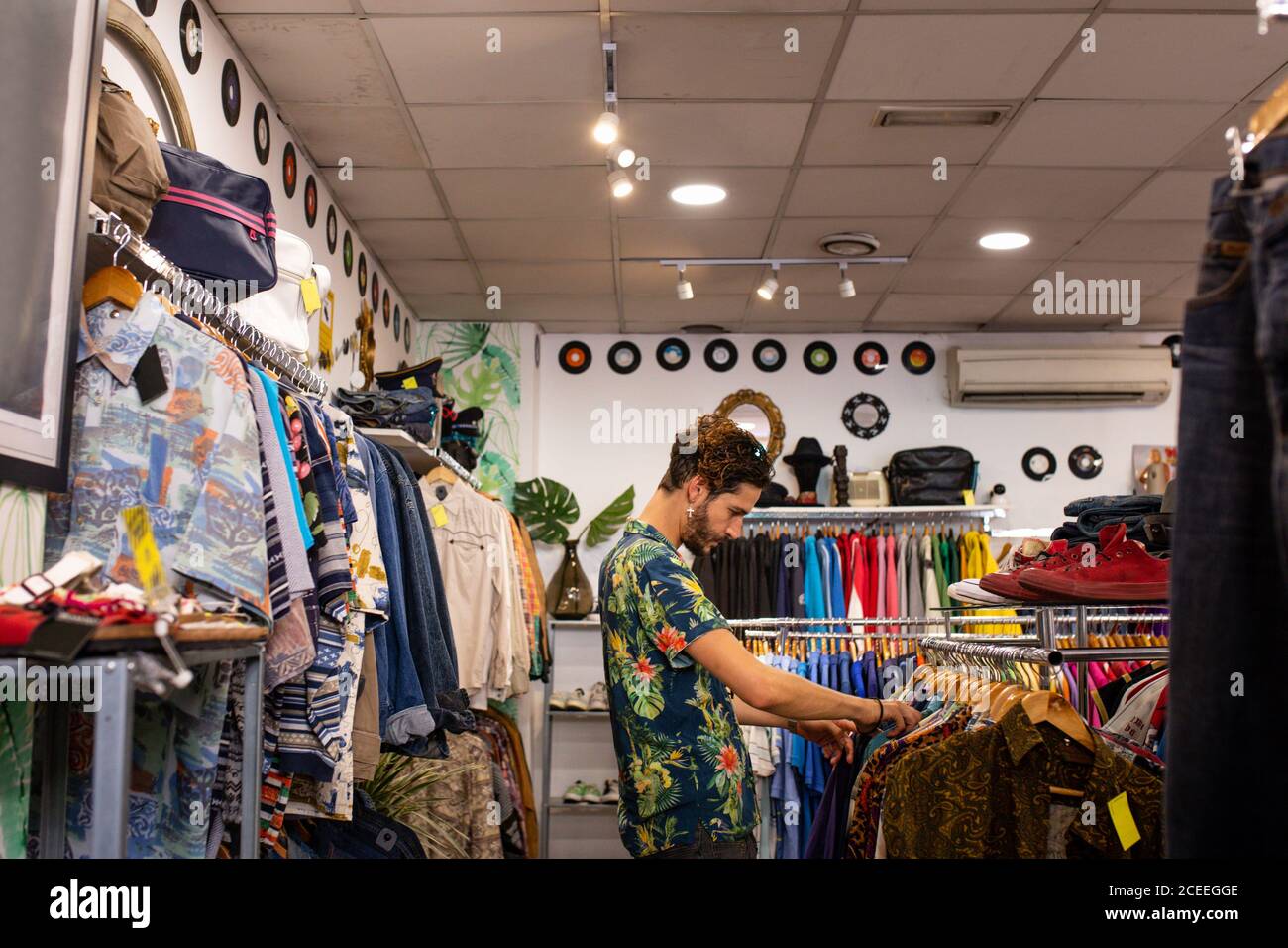 man smiling and picking garment from clothes rail while spending time ...