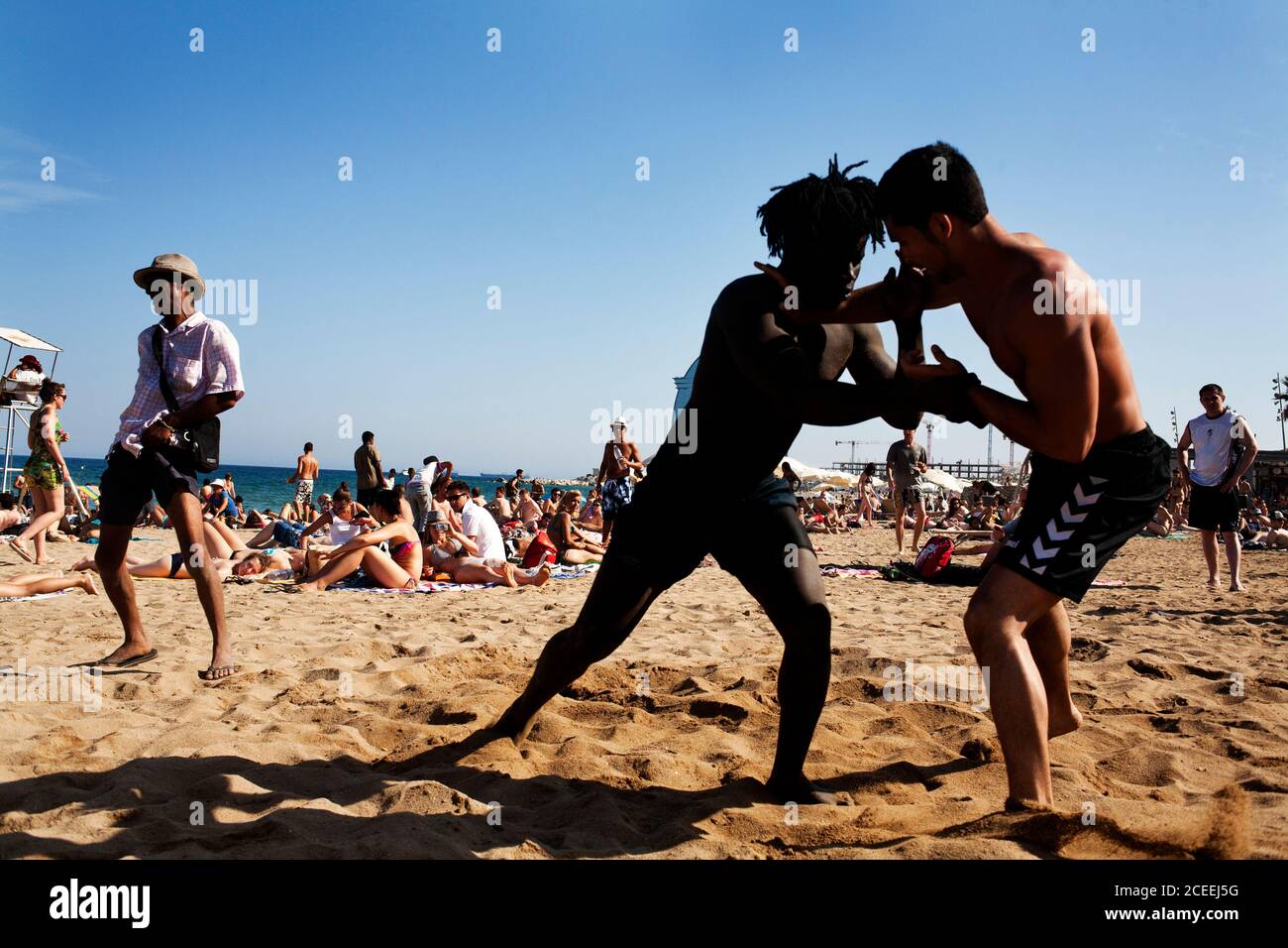 BARCELONA - July 10, 2011: ide view of two young men fighting on beach ...