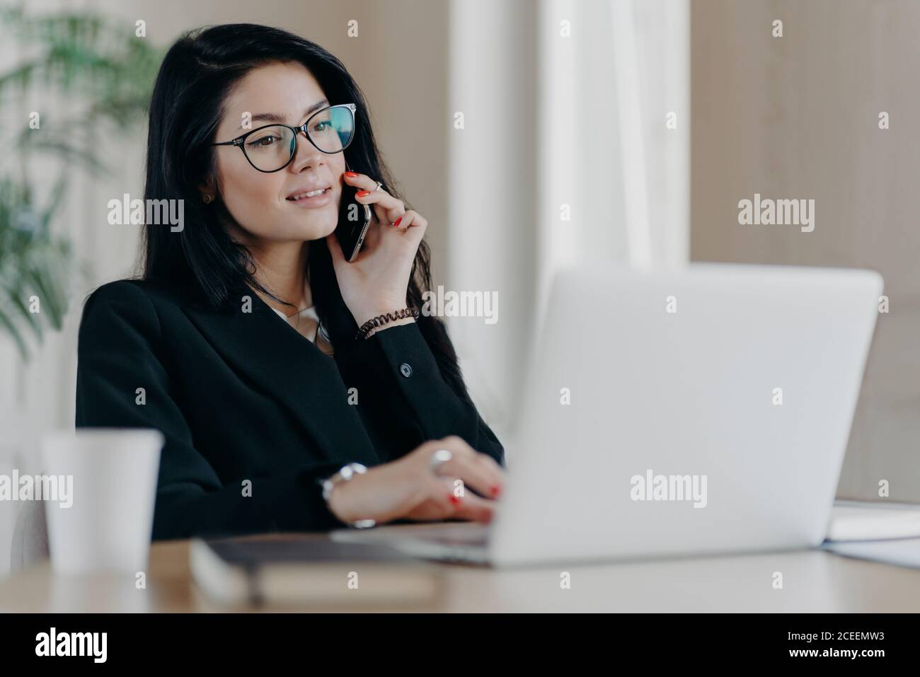 Confident serious business lady has phone conversation, poses in front ...