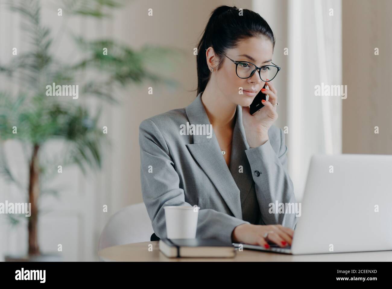 Serious brunette woman keyboards information, concentrated into laptop ...