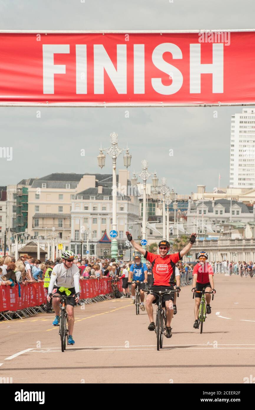 Riders cross the finish line after cycling from London to Brighton for ...