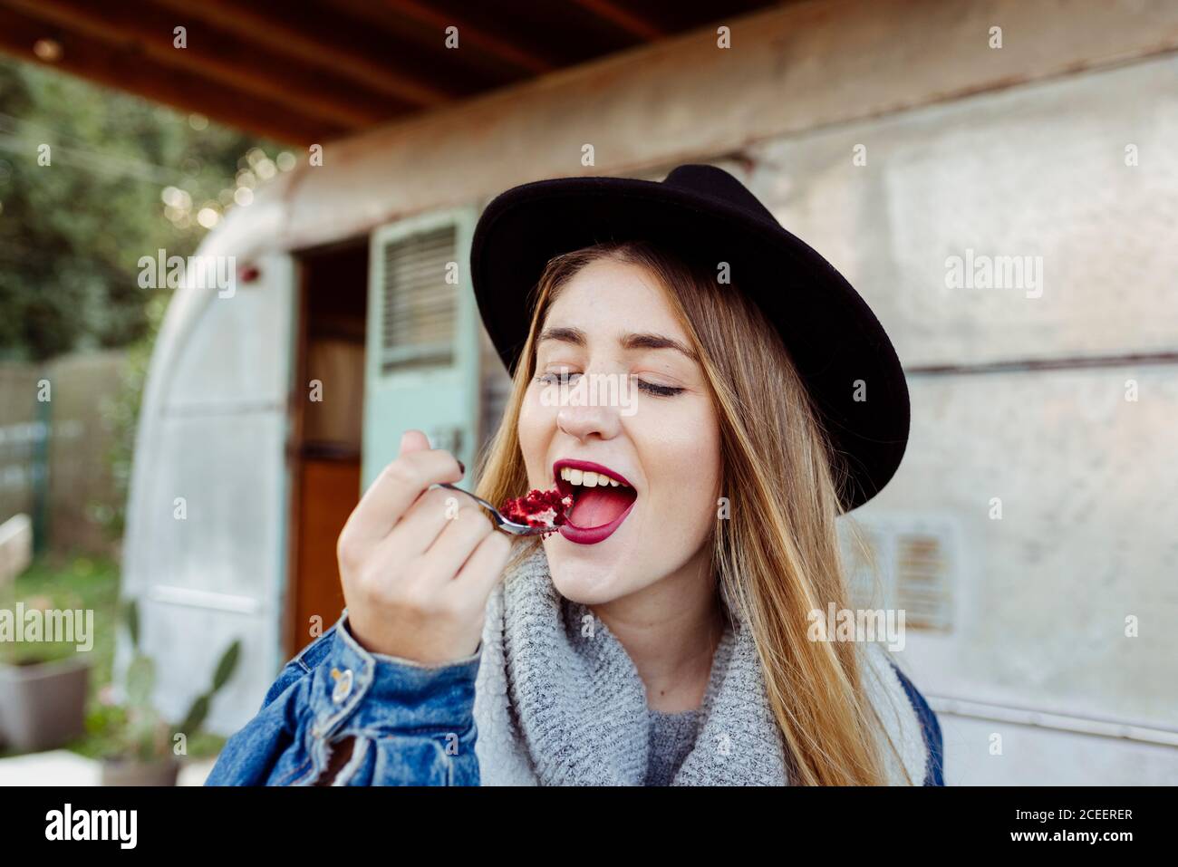 Pretty young female smiling and looking at camera while enjoying yummy ...
