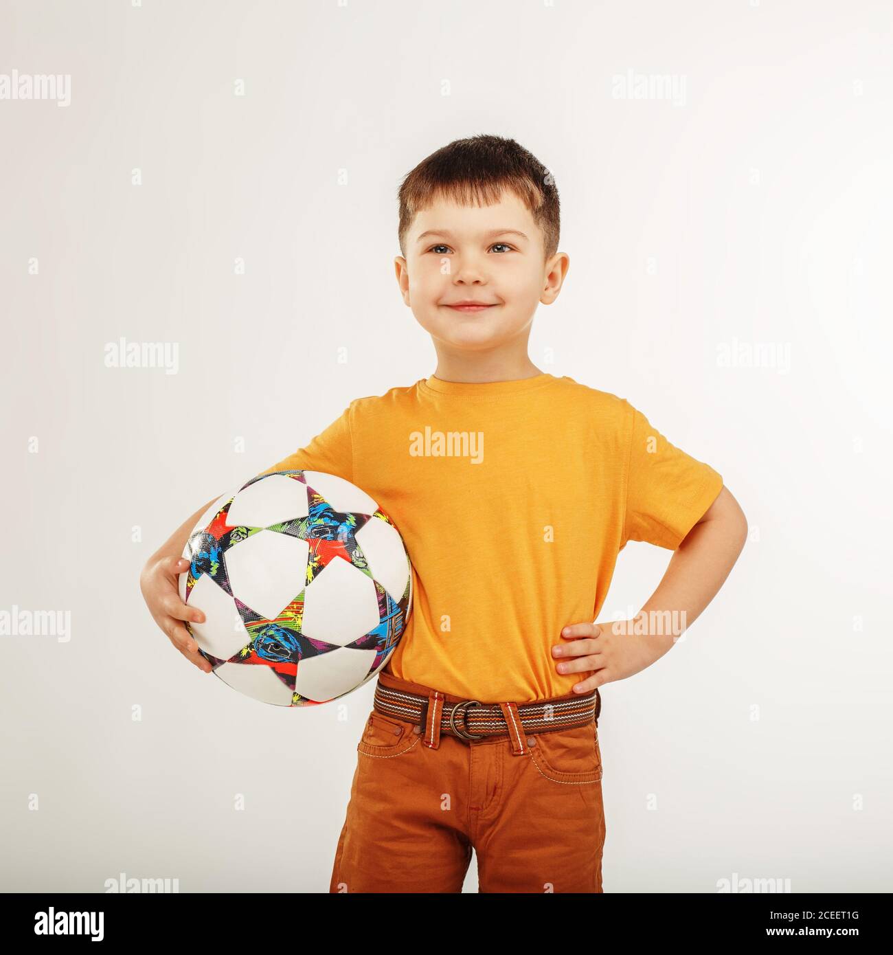little smiling boy holding a soccer ball under his arm Stock Photo - Alamy