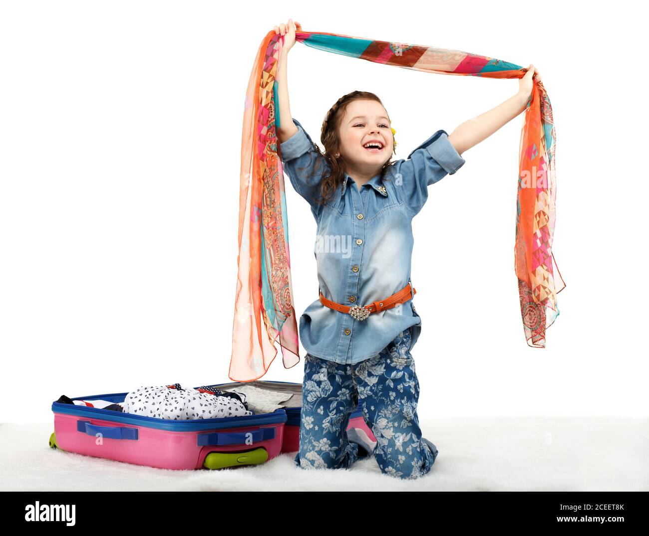 Fashionable little girl unpacking a suitcase isolated on white ...