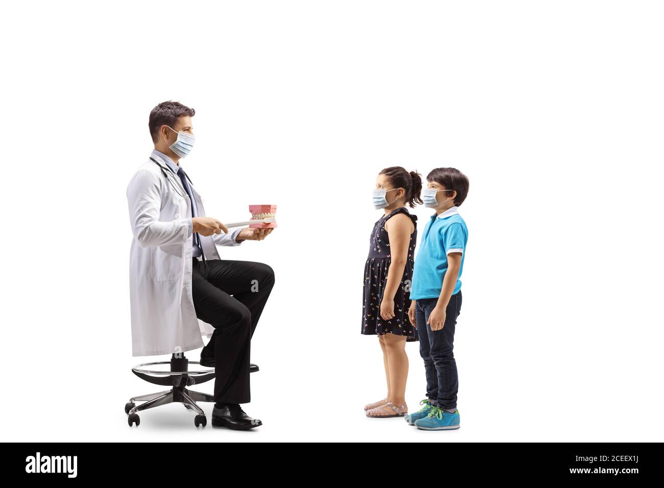 Dentist showing teeth brushing to a boy and girl with protective face ...