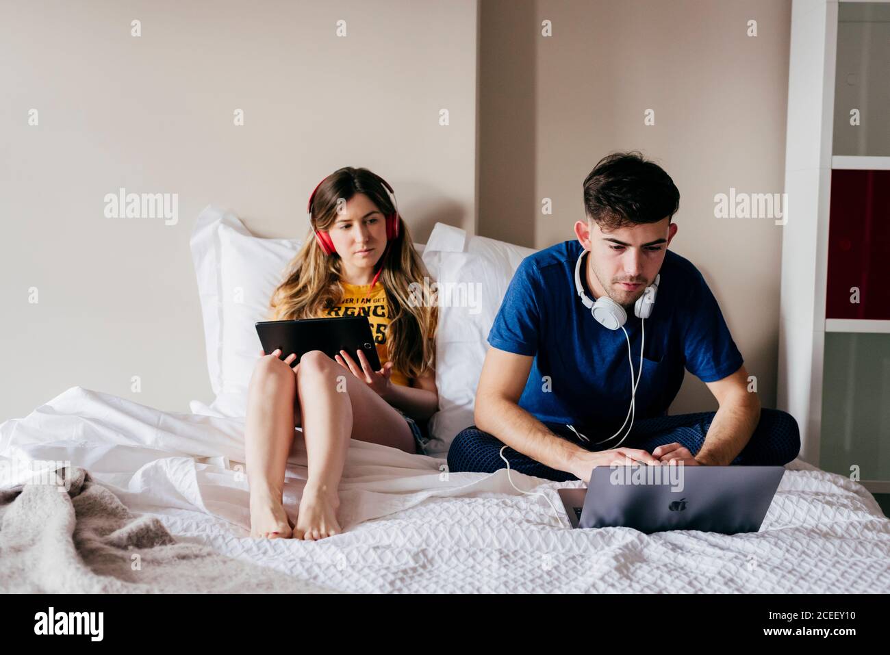 Couple with gadgets on bed Stock Photo - Alamy