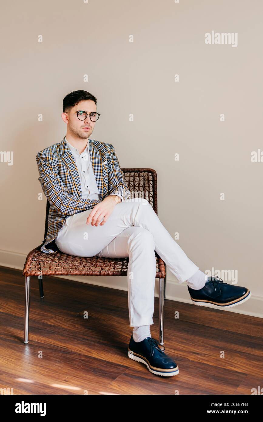 Thoughtful stylish young man on chair Stock Photo - Alamy