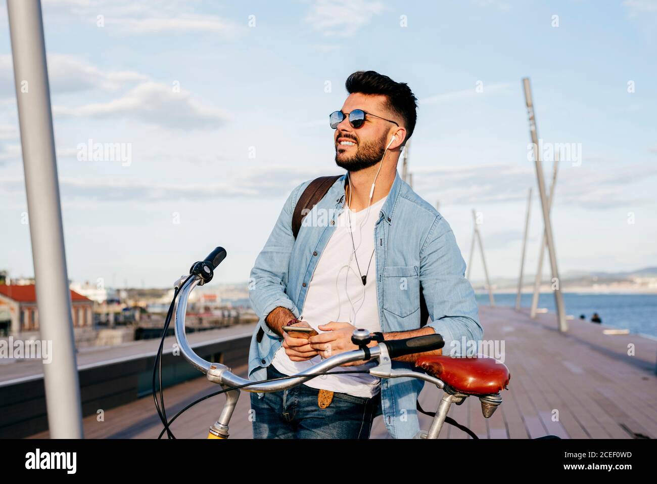 Smiling guy with bicycle and smartphone Stock Photo - Alamy