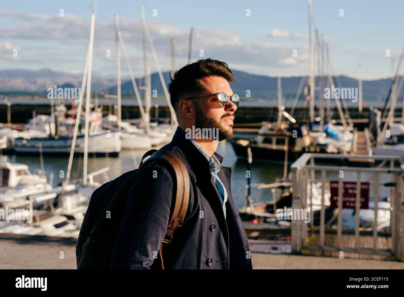 Side view of handsome trendy guy in sunglasses and with backpack ...