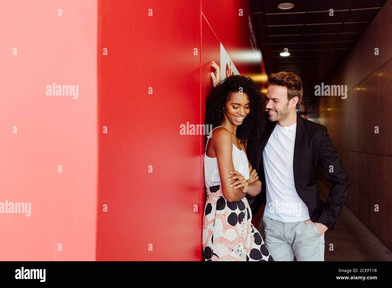 Handsome young guy leaning on red wall and flirting with beautiful ...