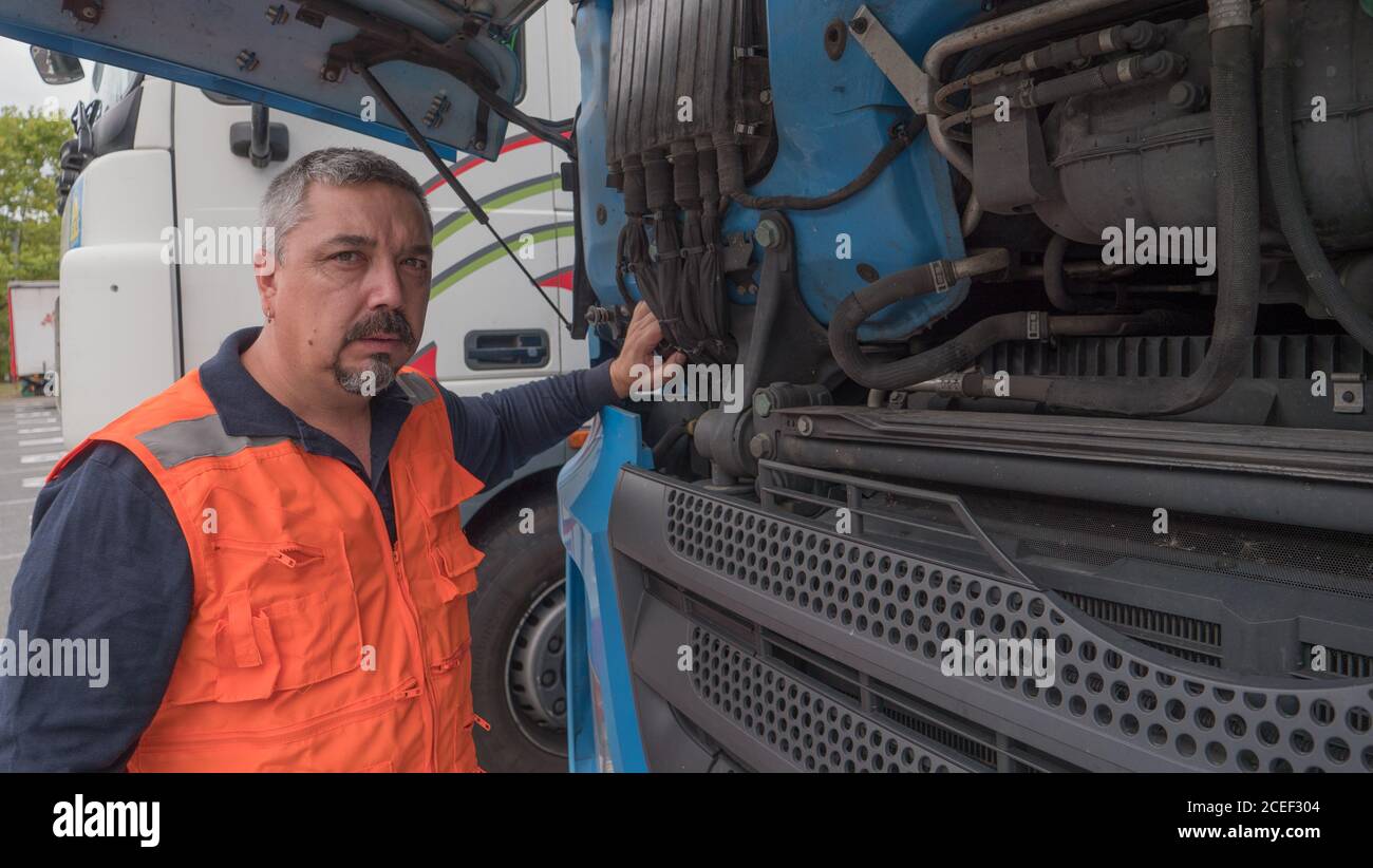 Male mechanic in an orange vest observing the engine of a truck Stock ...