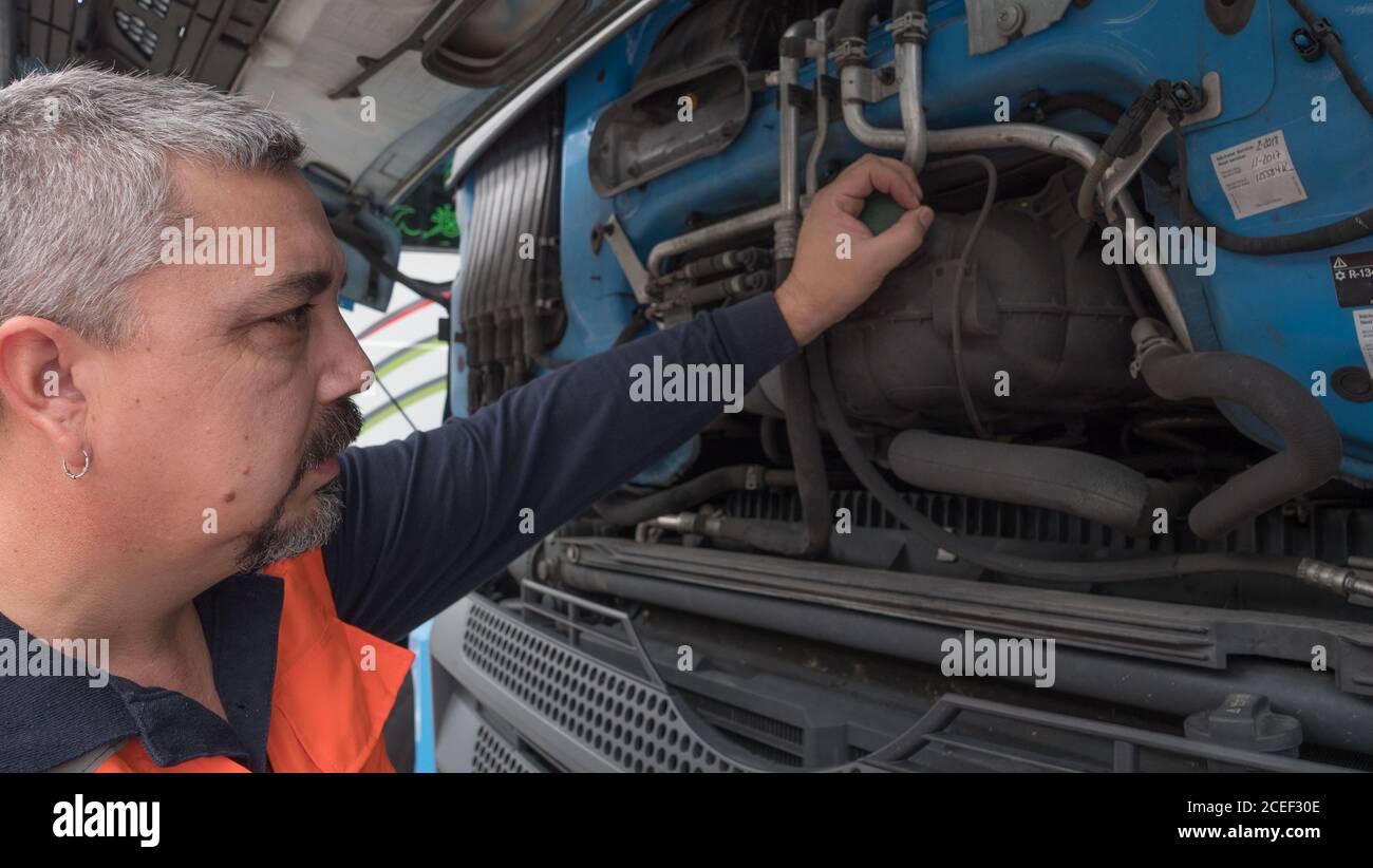 Male mechanic in an orange vest observing the engine of a truck Stock ...